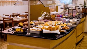 Buffet com diversos alimentos e um laptop no balcão.