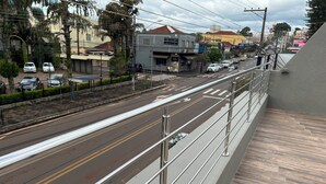 Vista de uma varanda com vista para uma rua com linhas de eléctrico, edifícios e carros estacionados.