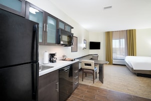 Quarto de hotel compacto com cozinha compacta, área de refeições, cama e televisão.
