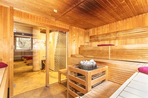 Uma sala de sauna de madeira com bancos, um banco com hidromassagem e uma pequena mesa com hidromassagem.
