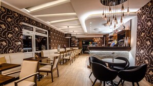 Restaurante moderno com área de bar, piso de madeira e papel de parede estampado.