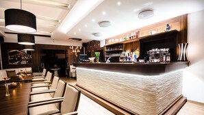 Uma área de bar moderna com balcão, assentos e uma variedade de garrafas e copos.