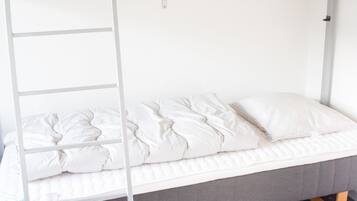Uma cama beliche com escada, colchão cinza e travesseiro branco.