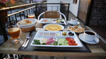 Uma mesa de café da manhã com diversos alimentos, incluindo pão, queijo e vegetais, além de xícaras de café e chá.