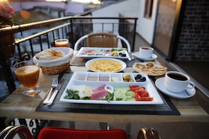 Uma mesa de café da manhã com diversos alimentos, incluindo pão, queijo e vegetais, além de xícaras de café e chá.