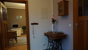 Um corredor com uma mesa de madeira, uma máquina de costura e um vaso com flores.
