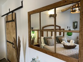 Quarto com um espelho grande, estrutura de cama de madeira e decoração rústica.