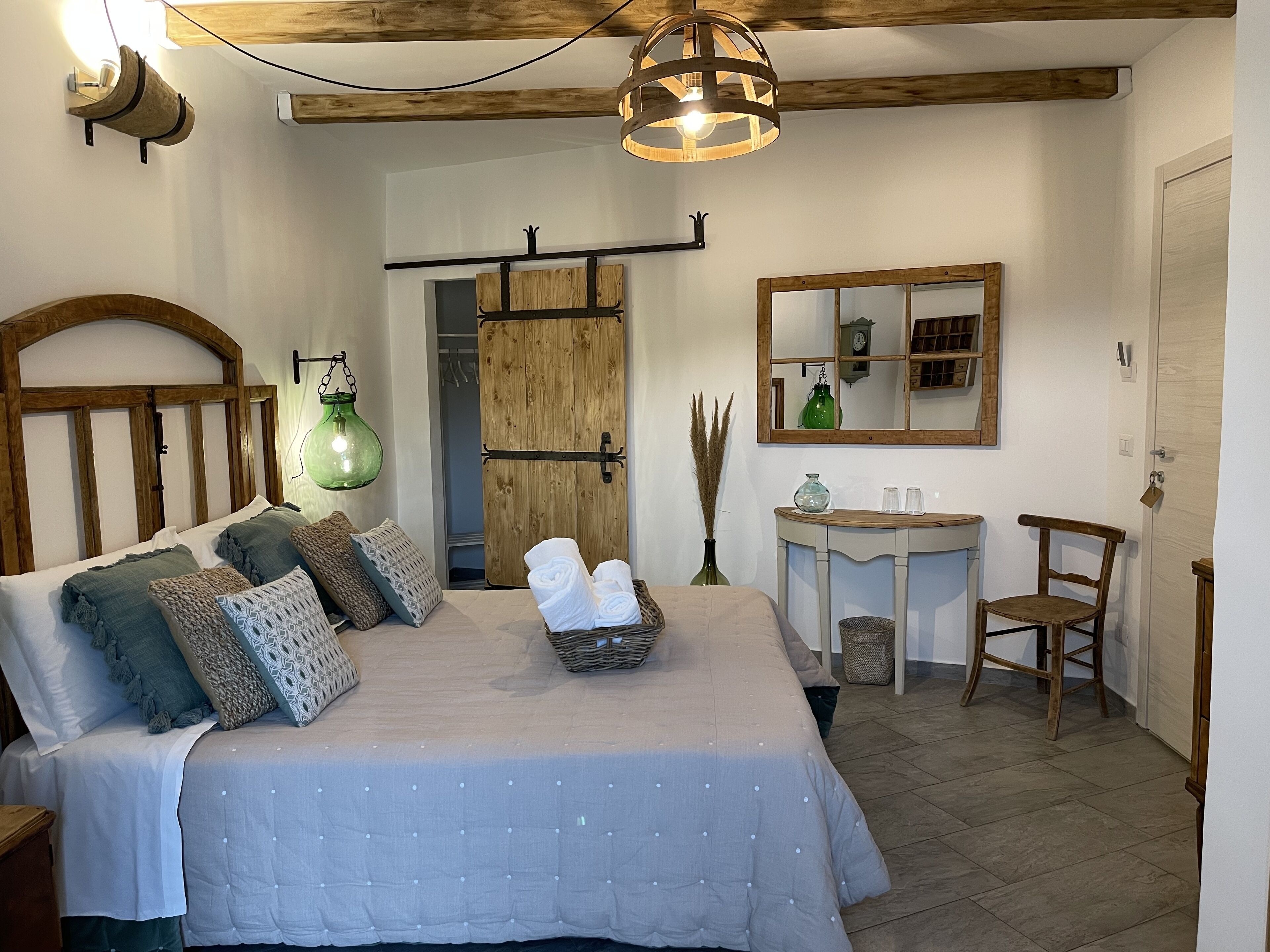 Quarto com cama, mesa de cabeceira, cadeira e espelho.