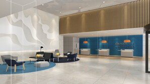 Uma área de recepção moderna com parede estampada em azul, dois balcões de atendimento e um espaço de estar com sofás e mesa de centro.