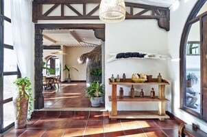 Um corredor com um banco de madeira, uma prateleira com objetos decorativos e uma janela grande com vista para o exterior.