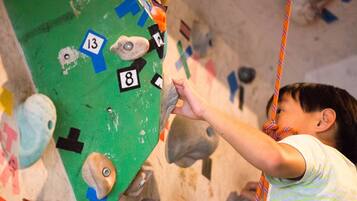 Criança escalando uma parede de escalada com apoios numerados.