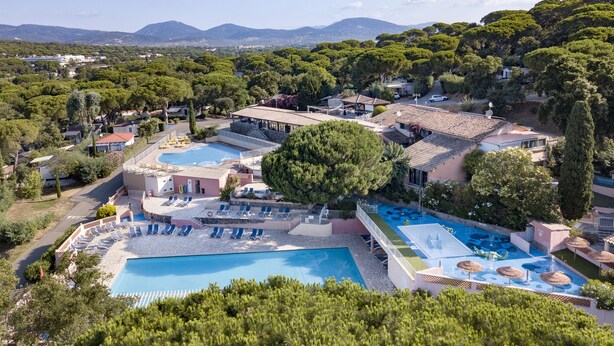 Resort com várias piscinas, área coberta e vegetação exuberante.