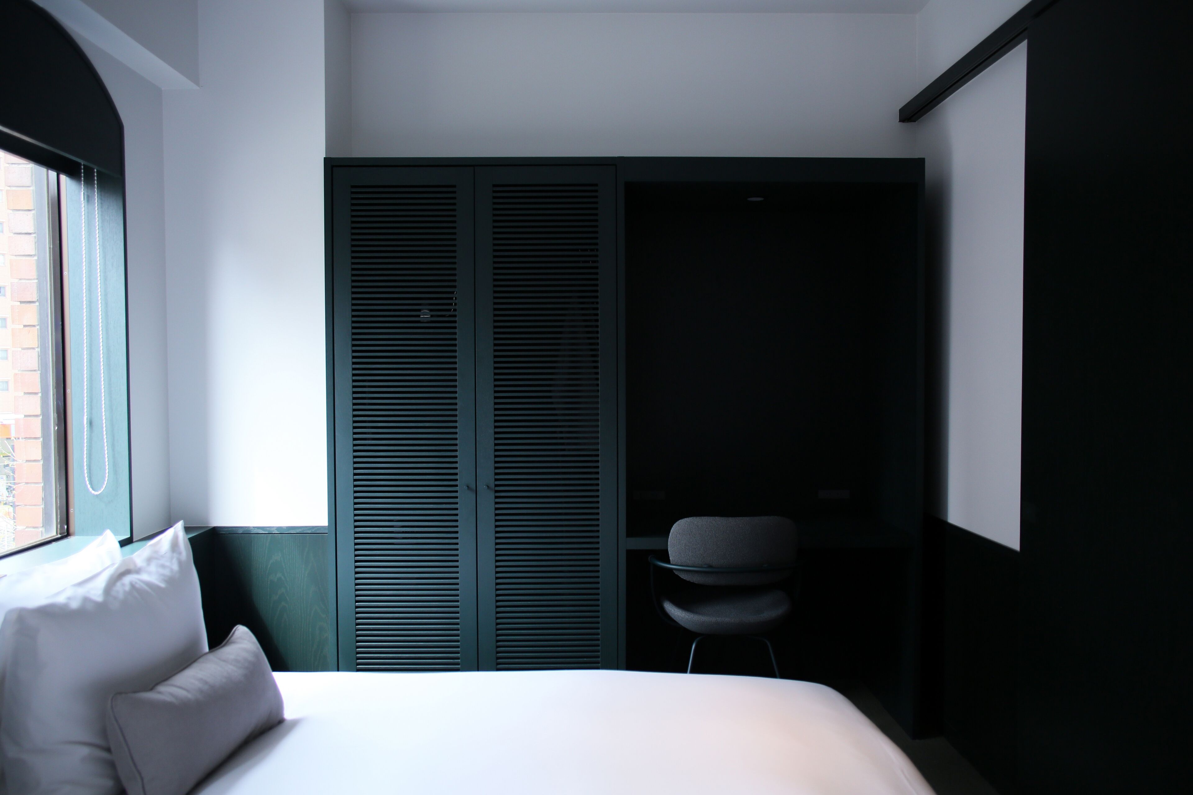 Um quarto moderno com uma cama, uma cadeira e um guarda-roupa.