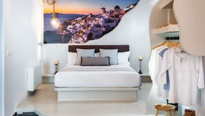 Quarto moderno com cama curva, vista para uma cidade costeira, um banquinho de madeira e um cabideiro.
