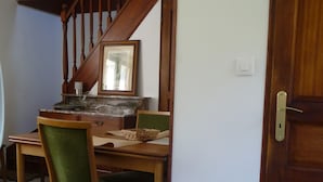 Uma área de refeições com mesa de madeira, cadeiras e escada.