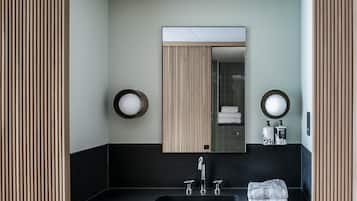 Casa de banho moderna com lavatório preto, dois espelhos redondos e um espelho grande sobre o lavatório.