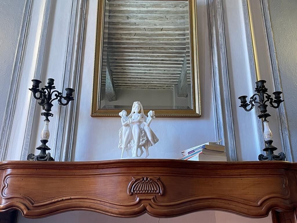 Quarto com cômoda de madeira, espelho e uma estátua sobre a cômoda.