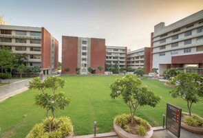 Um pátio central com gramado, ladeado por edifícios de vários andares com varandas.