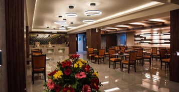 Um hall de hotel com balcão de recepção, área de estar e luminárias modernas.