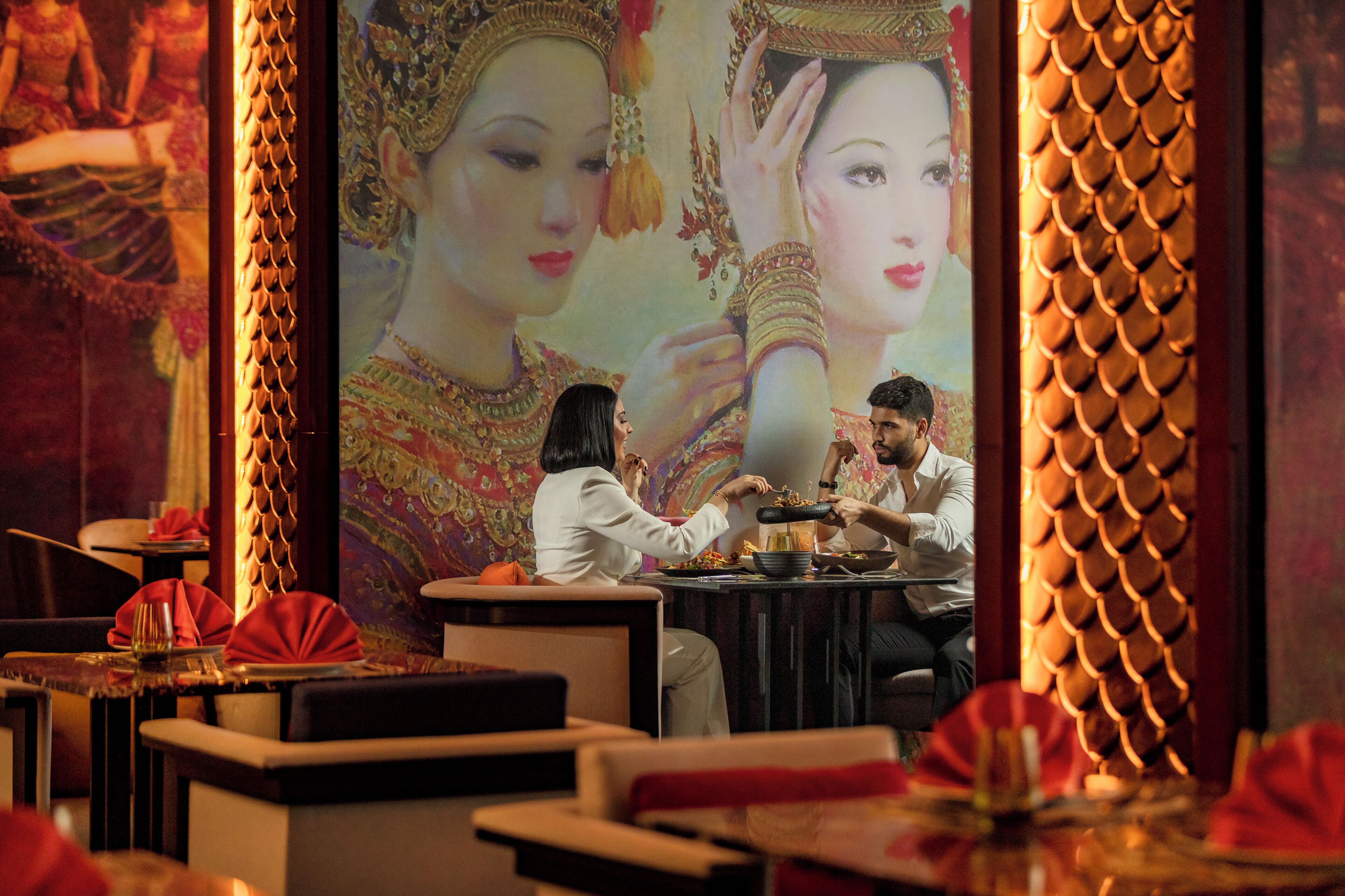 Um restaurante com decoração tradicional, incluindo pinturas elaboradas nas paredes e um padrão de escamas de peixe na parede.