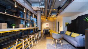 Um interior moderno com área de bar, assentos e um sofá.