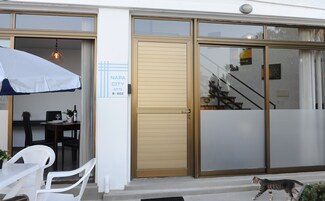 Um edifício residencial com uma porta de vidro deslizante, uma área de jantar com mesa e cadeiras, e um gato andando nas escadas.