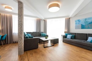 Uma sala de estar moderna com um sofá cinzento, uma mesa de centro e um espaço de jantar com uma cadeira.