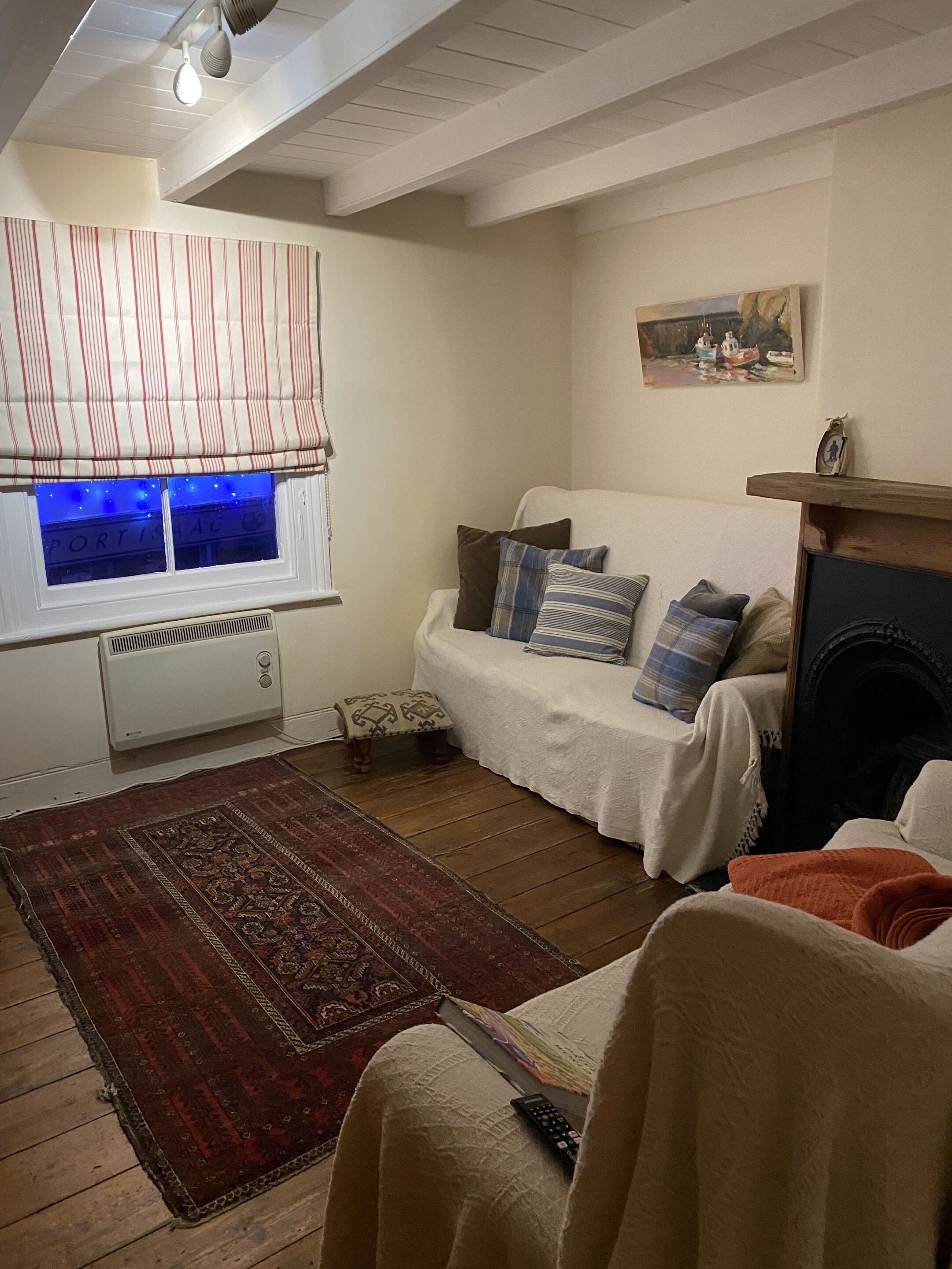 Uma sala de estar aconchegante com sofá, lareira, tapete e janela com cortinas.