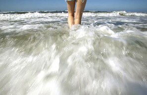 Uma pessoa em pé na água, com ondas ao redor.
