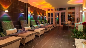 Uma área de spa com várias cadeiras reclináveis, um balcão de recepção e uma grande janela.