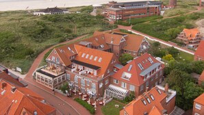 Um hotel com vários edifícios, uma praia ao fundo e um farol.