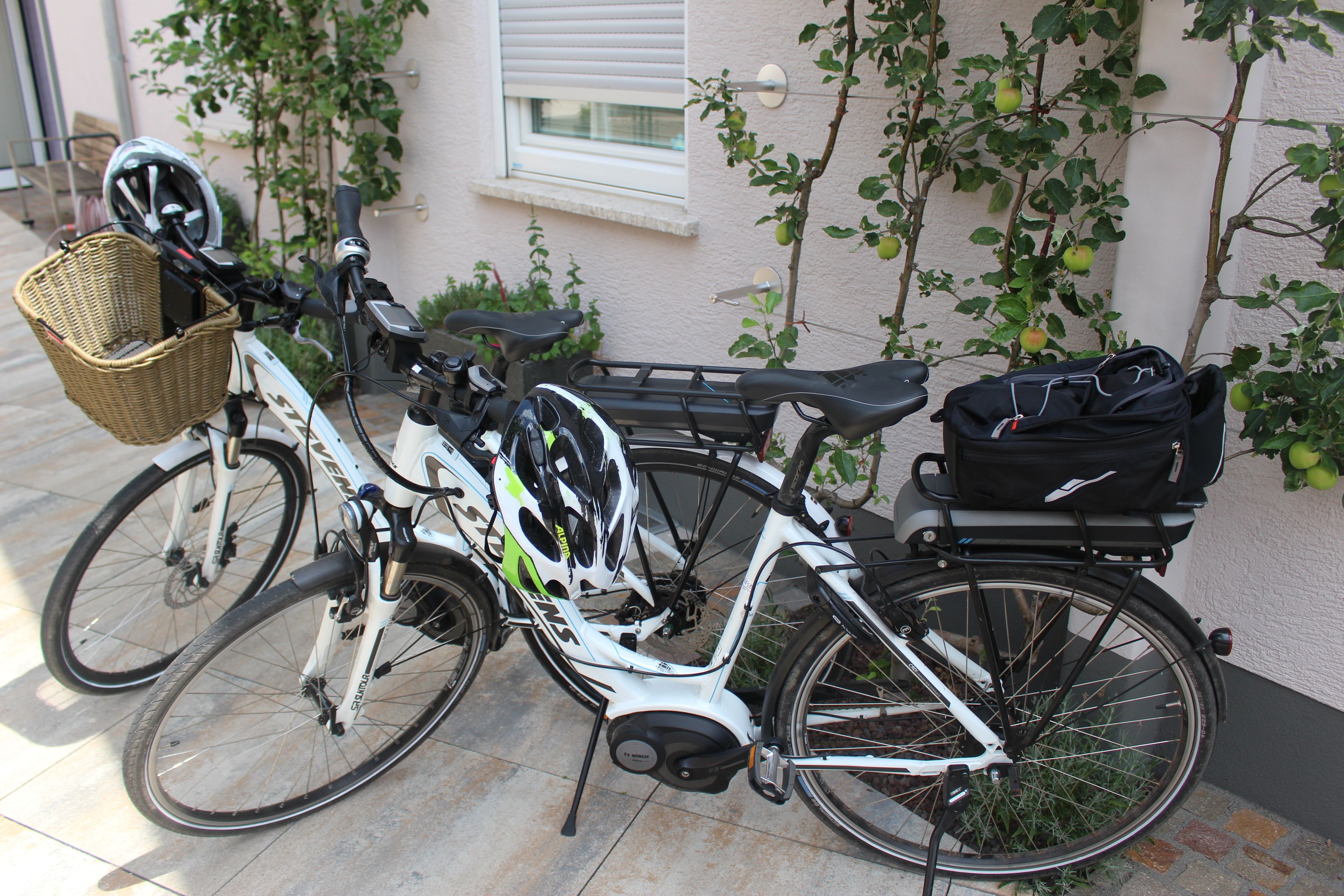 Uma bicicleta com cesto e bolsa fixados na parte traseira, estacionada em piso de azulejos.