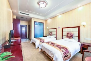 Quarto de hotel com duas camas, uma escrivaninha e uma televisão.