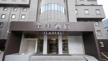 Entrada de hotel com fachada moderna, janelas amplas e uma placa com a inscrição 'JI HOTEL'.