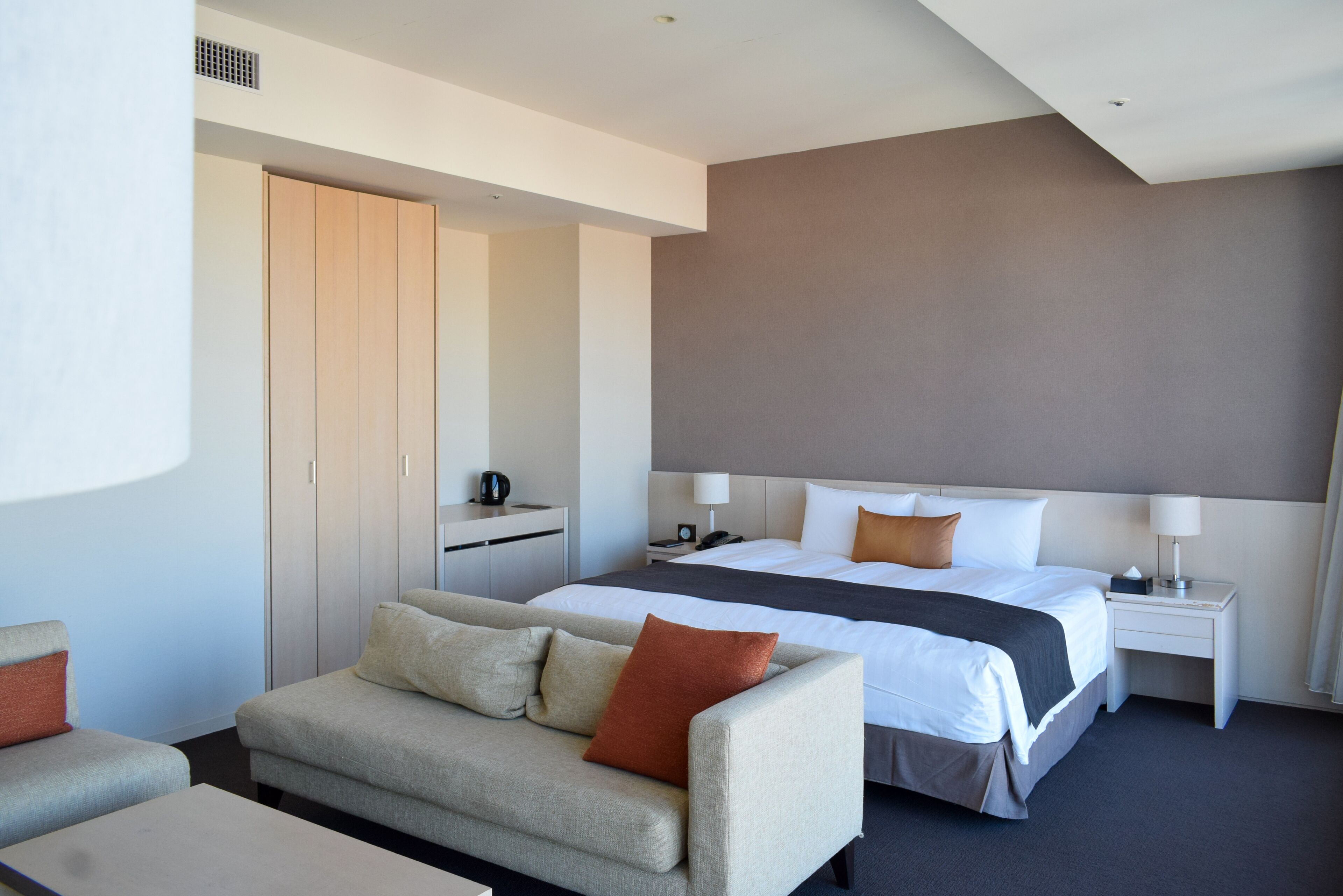 Quarto de hotel com cama, sofá, escrivaninha e guarda-roupa.