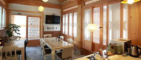 Um quarto em estilo japonês tradicional com tatames, uma mesa baixa e um conjunto de chá, e portas corrediças com desenhos de treliça.