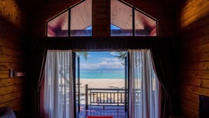 Uma cabana de madeira com varanda e vista para a praia.