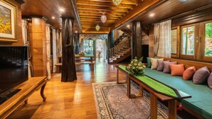 Um interior em madeira com sofá, mesa e escada.