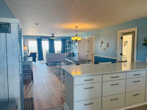 Uma cozinha moderna com armários brancos, uma ilha central e um espaço de refeições com vista.