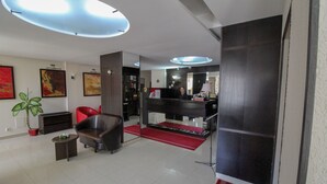Um lobby moderno com balcão de recepção, área de estar e obras de arte nas paredes.
