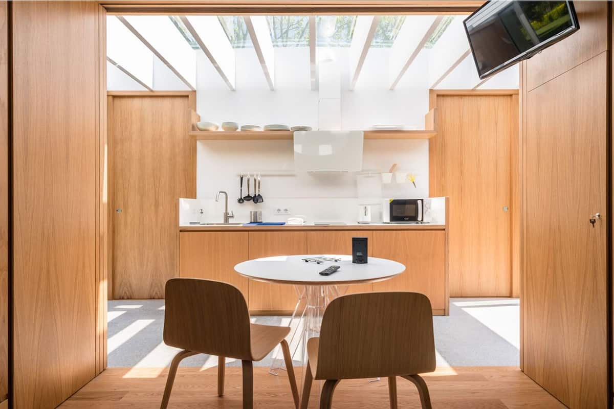 Uma cozinha moderna com uma ilha central, duas cadeiras e uma TV fixada na parede.