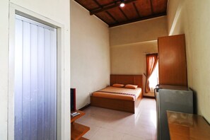 Quarto com cama, escrivaninha, guarda-roupa e porta.