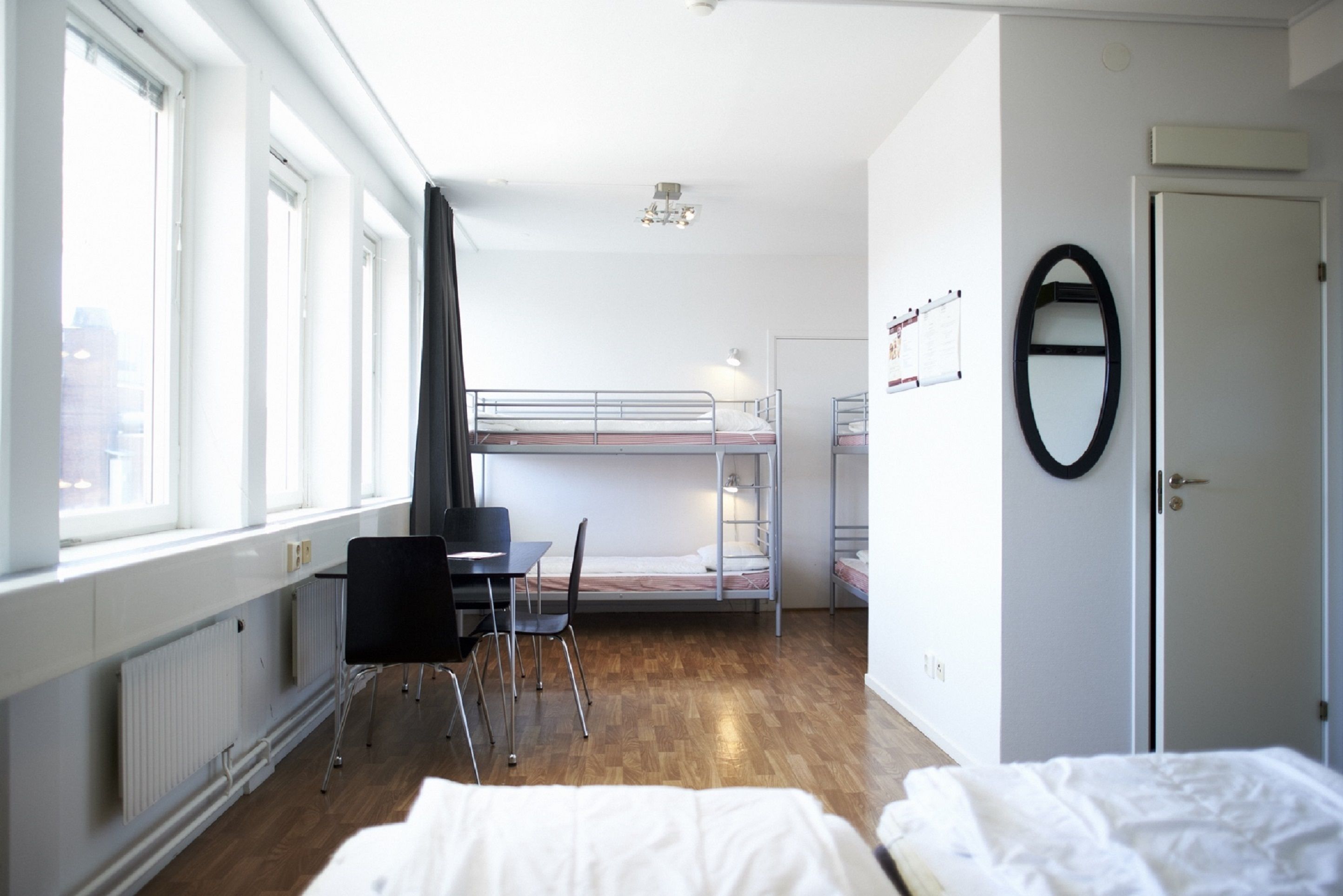 Quarto em dormitório com beliches, escrivaninha e cadeira.