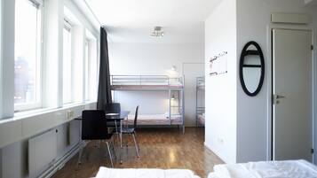 Quarto em dormitório com beliches, escrivaninha e cadeira.