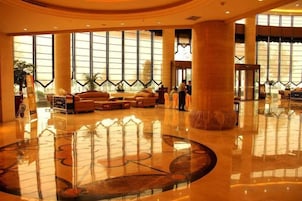 Um hall amplo com piso lustroso, grandes janelas e área de estar central.
