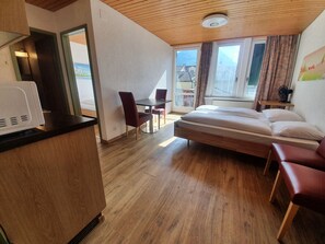 Quarto de hotel com teto de madeira, cama, escrivaninha e cadeira.
