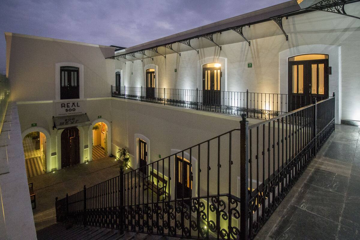 Um hotel com área externa coberta, escadas e várias portas.