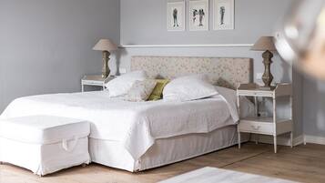 Quarto bem arrumado com cama, mesas de cabeceira e criado-mudo.