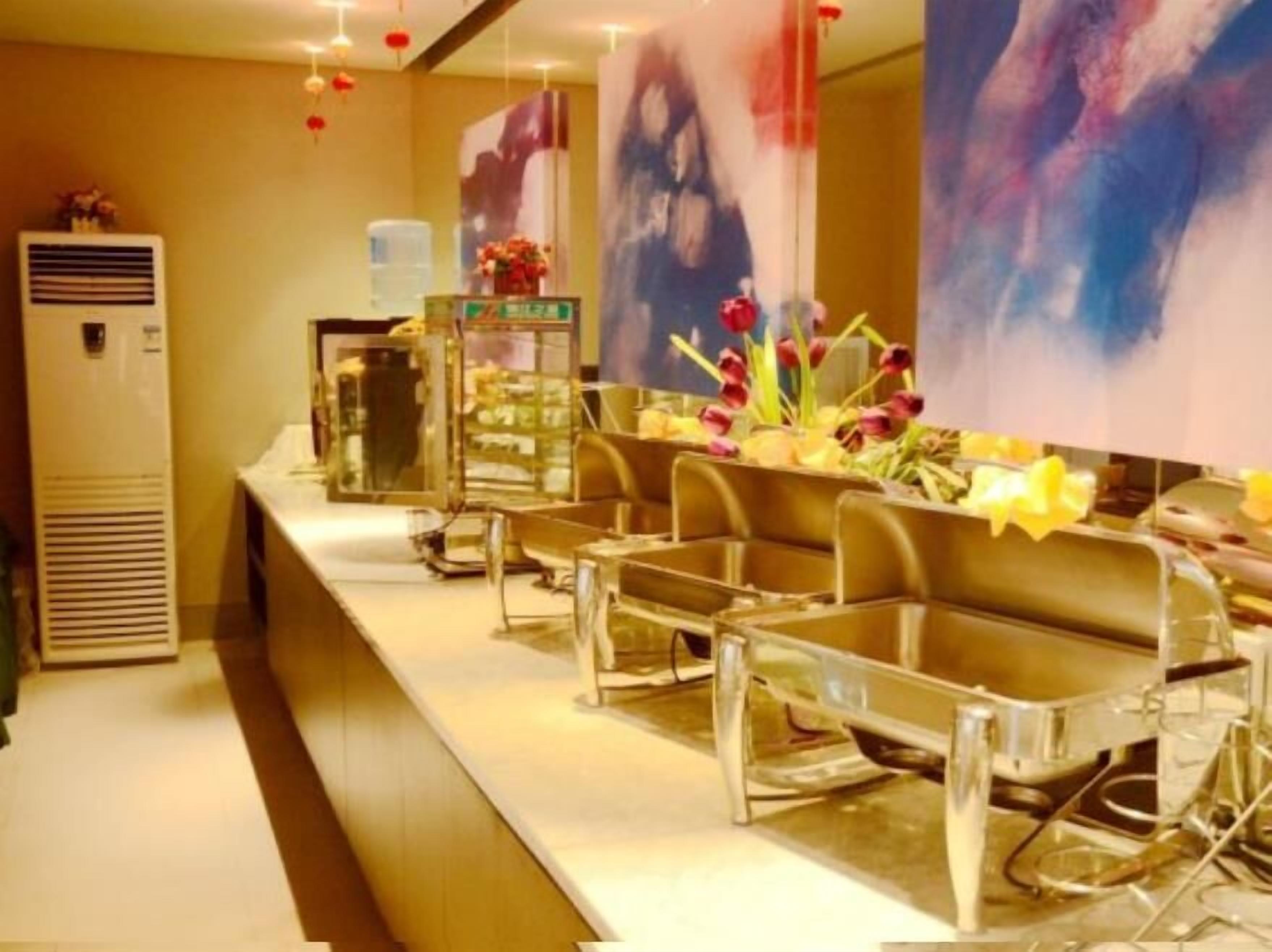 Uma área de buffet com estações de servir em vidro transparente, um dispensador de água e uma geladeira.