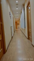 Um corredor com portas de madeira, piso claro e iluminação no teto.